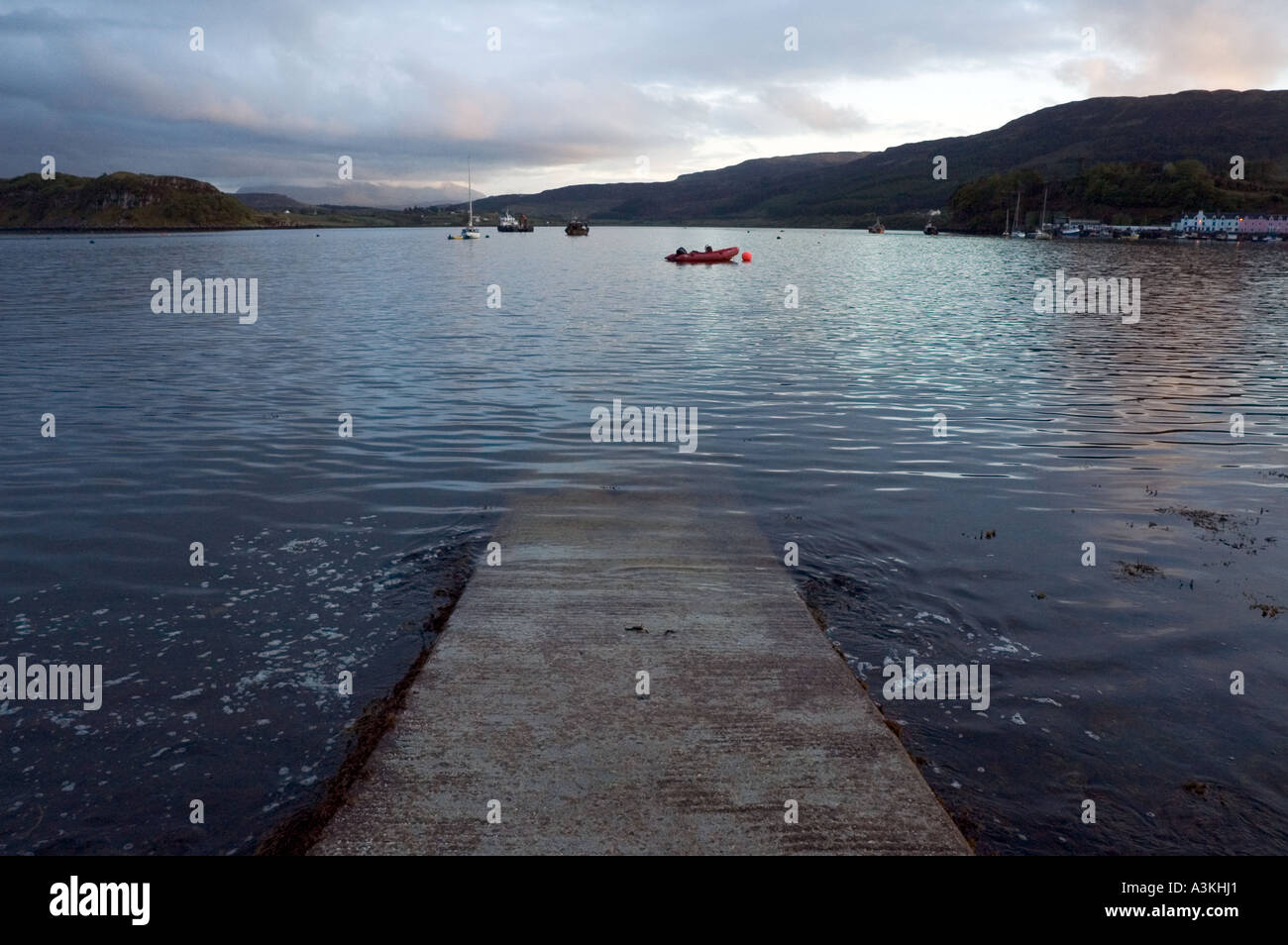 A cement walkway leads into the harbour of Portree Isle of Skye ...