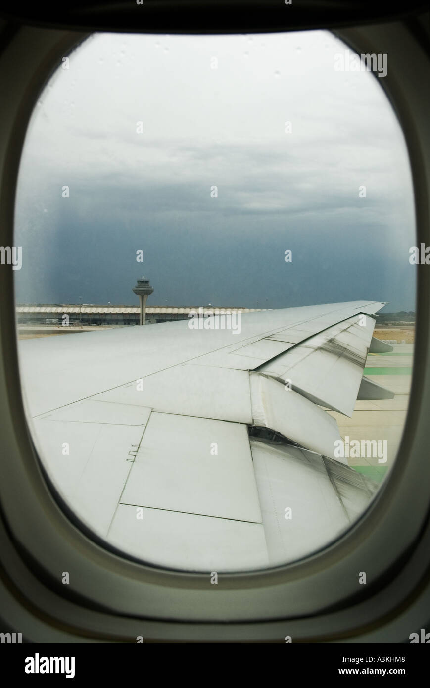 View out of passenger s round window of an airplane's wing on the ...
