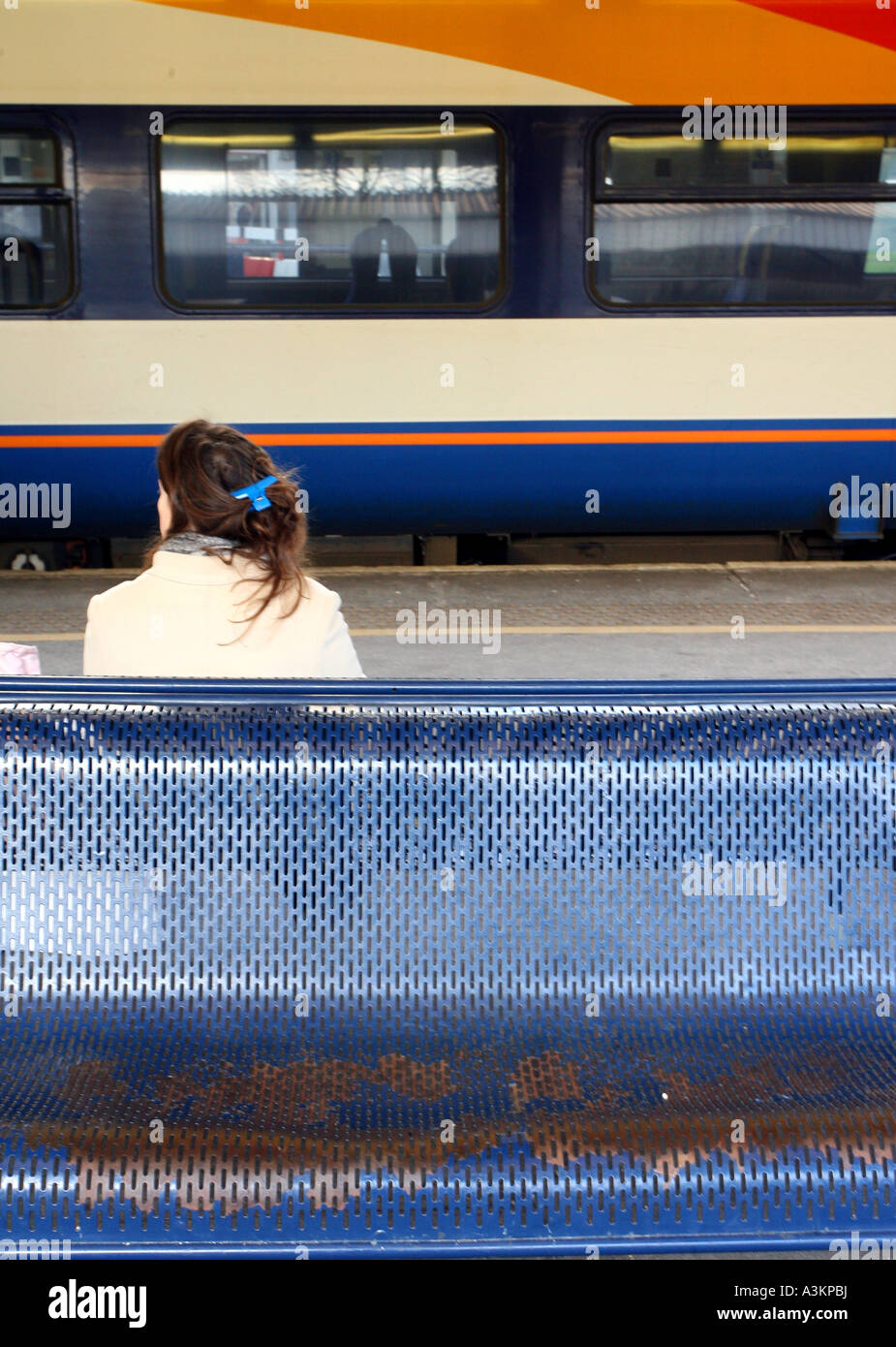 A train goes past as a woman passenger waits for a train on the ...