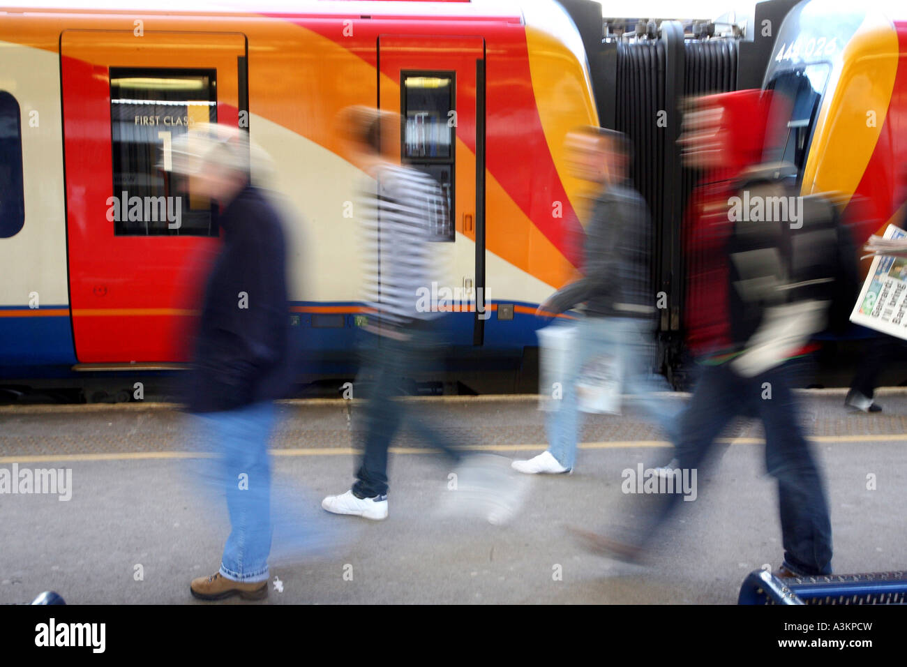 Passengers walking down the platform with train in background Stock ...