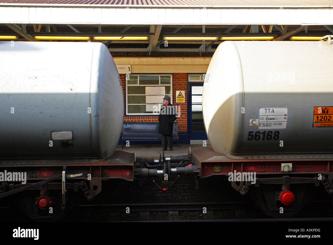 A train goes past as a man passenger waits for a train on the platform ...