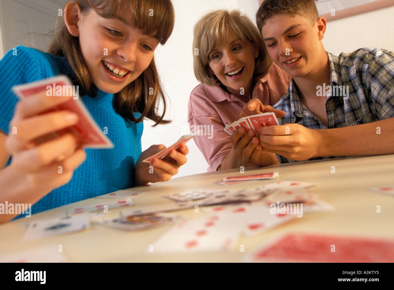 Mother watching siblings play cards Stock Photo - Alamy