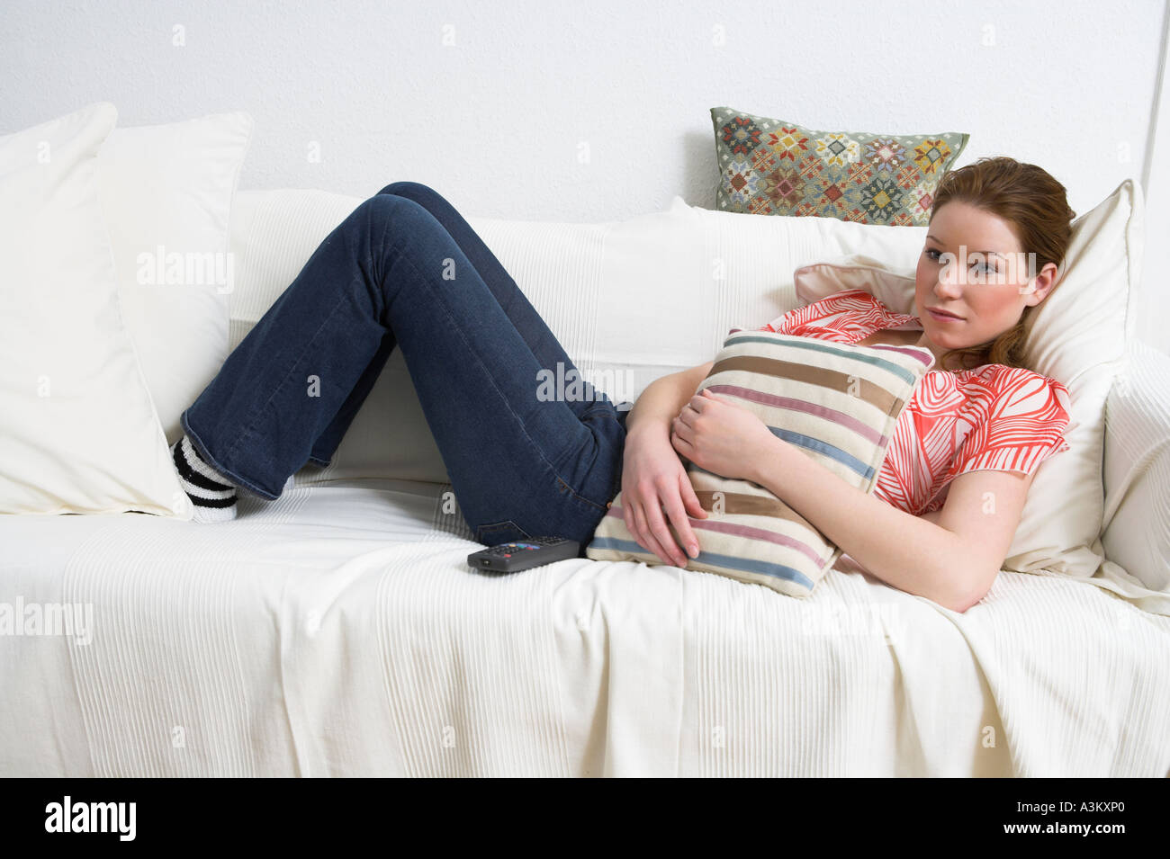 teenage with melancholic expression lying on couch and watching tv ...