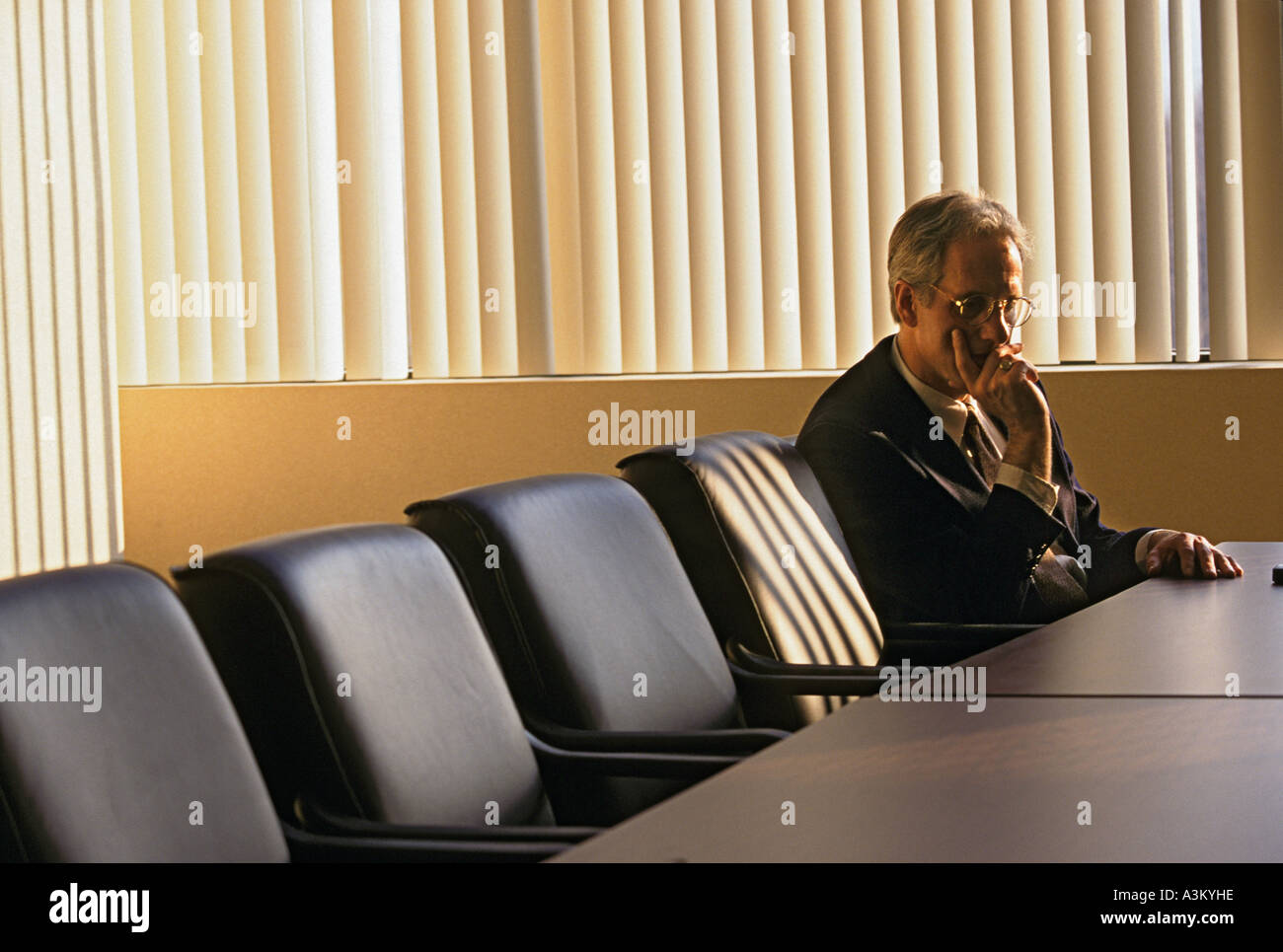 Pensive executive sitting alone in boardroom Stock Photo - Alamy