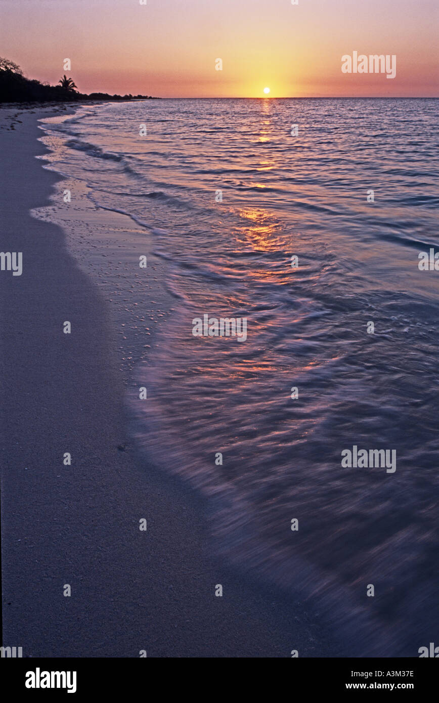 Quiet waves lap island beach as sun rises over ocean Bahia Honda State ...