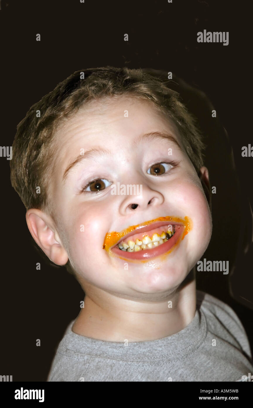 Young 4 year old boy with bright orange icing covering his mouth after ...