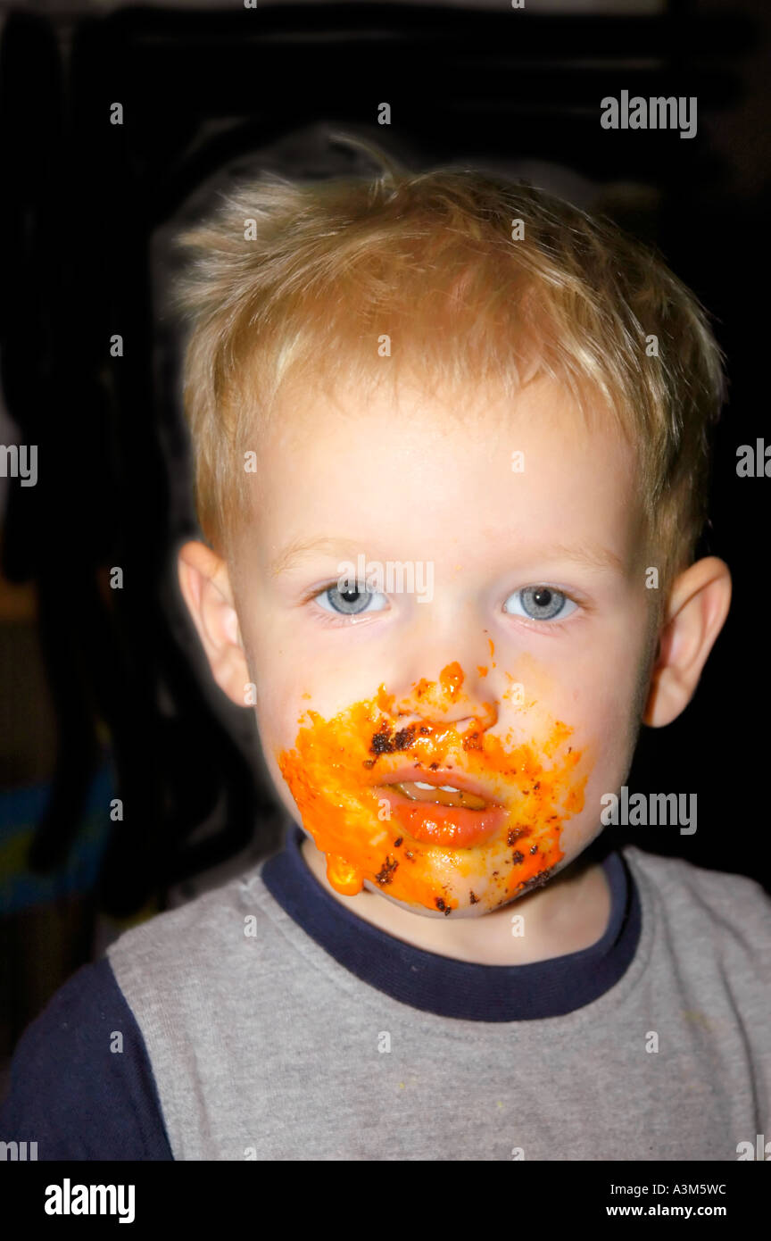 Young 1 to 2 year old boy with bright orange icing covering his face ...