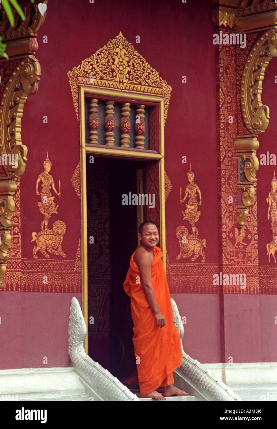 A smiling monk on the steps of a temple building in Luang Prabang, Laos ...