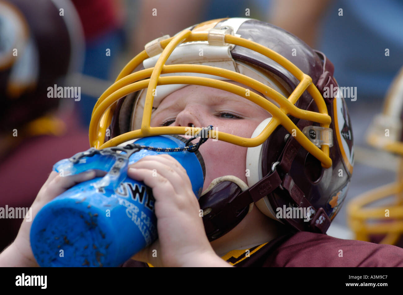 Kids full contact football player drinking water in heat of game Stock ...