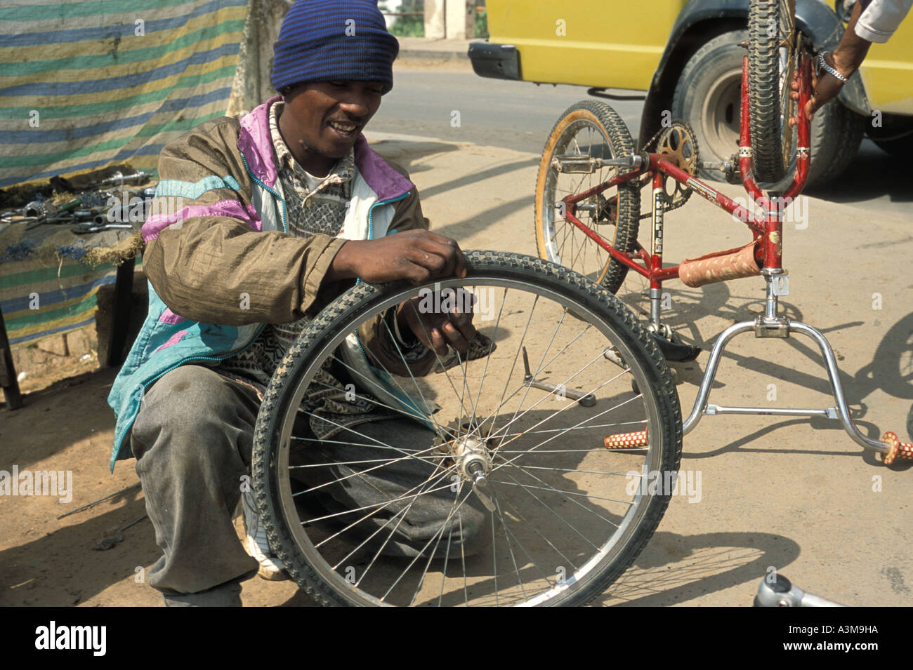 Black African man doing bicycle repairs outside of Beira Mozambique ...