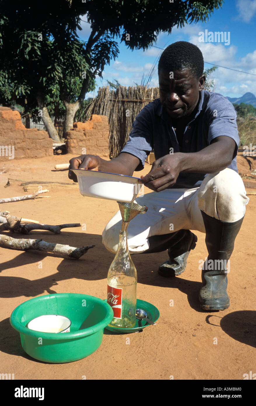Black African man pouring sunflower oil from sunflower seed press in ...
