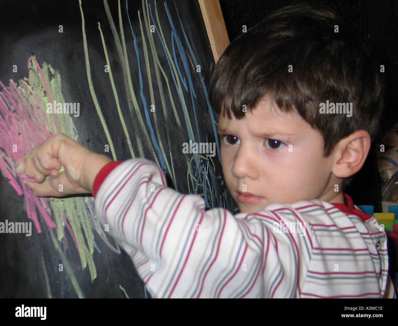 ANGRY BOY DRAWING WITH CHALK AT BLACK CHALK BOARD Stock Photo - Alamy