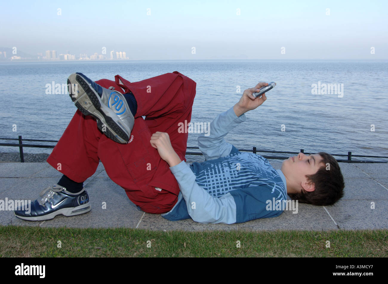 teenager boy lying down looking to the mobile phone Stock Photo - Alamy