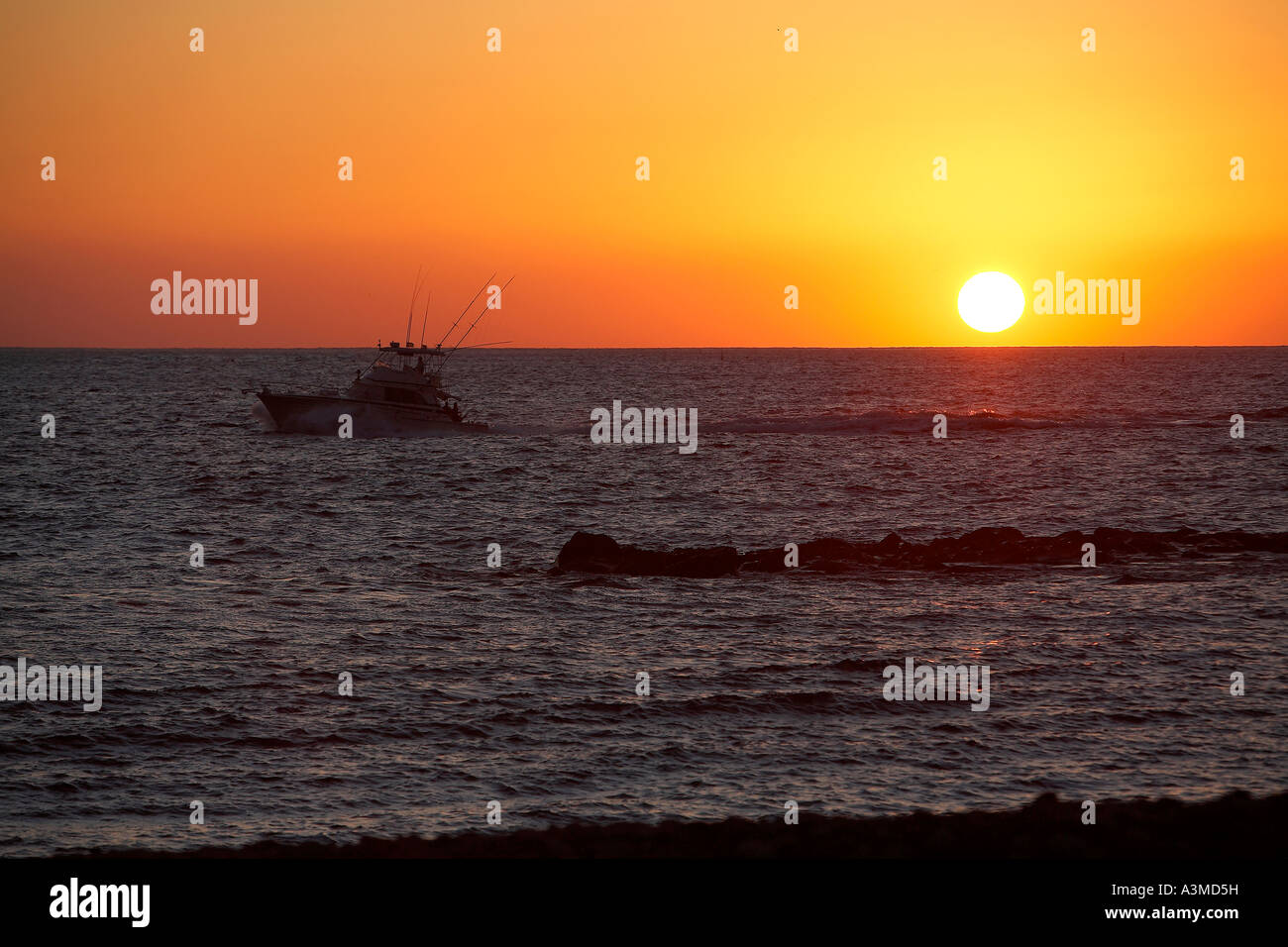 An horizon sunset with the ocean and a silhouette of a small boat in ...