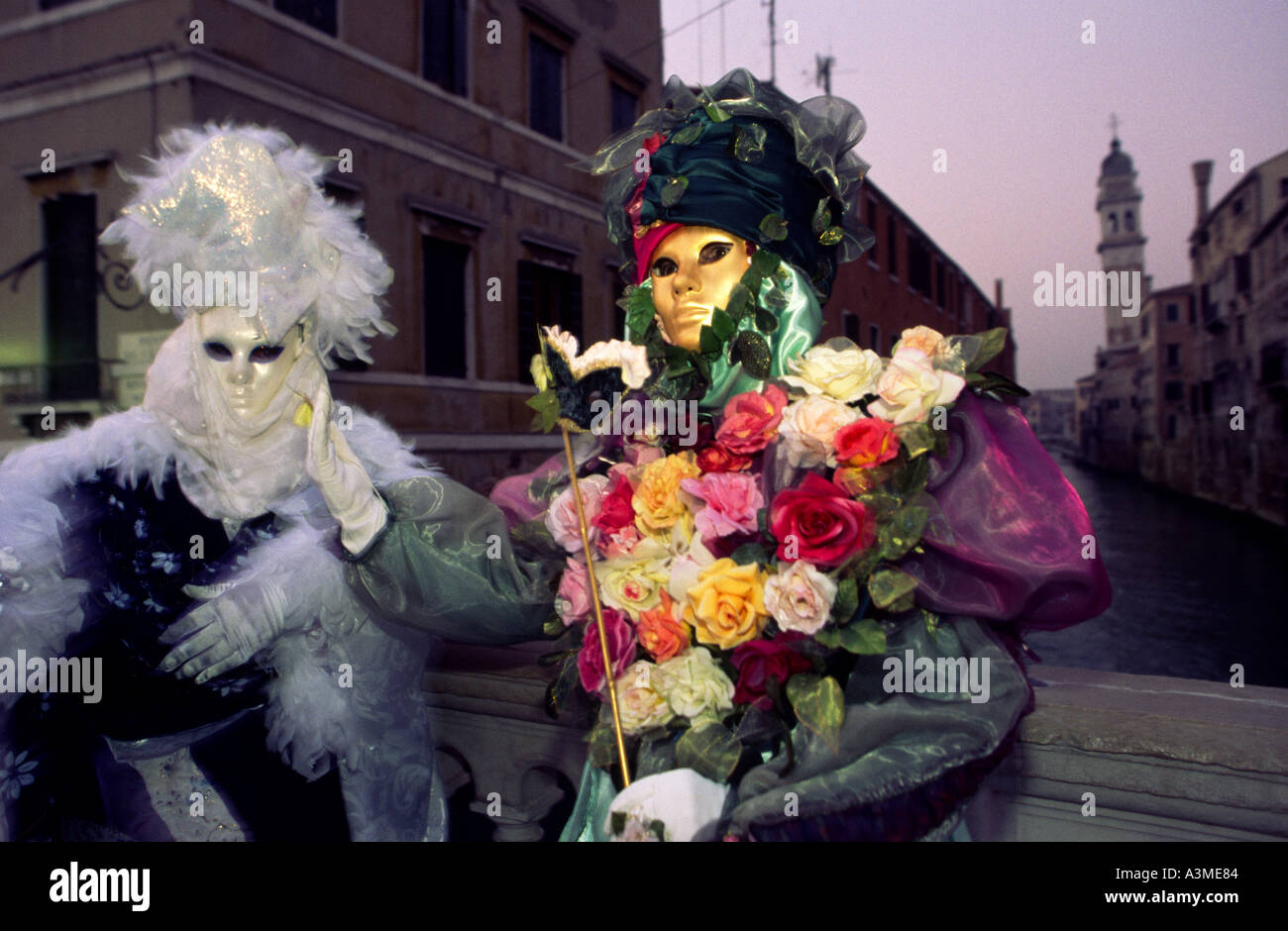 Two people on a small bridge over canal dressed in lavish costumes and ...