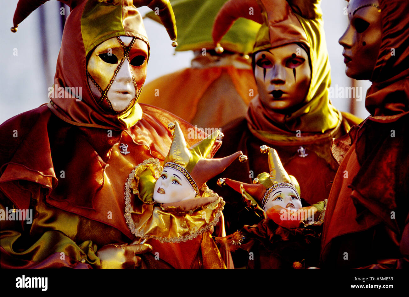 Two people dressed in bright red gold jester costumes and masks for the ...