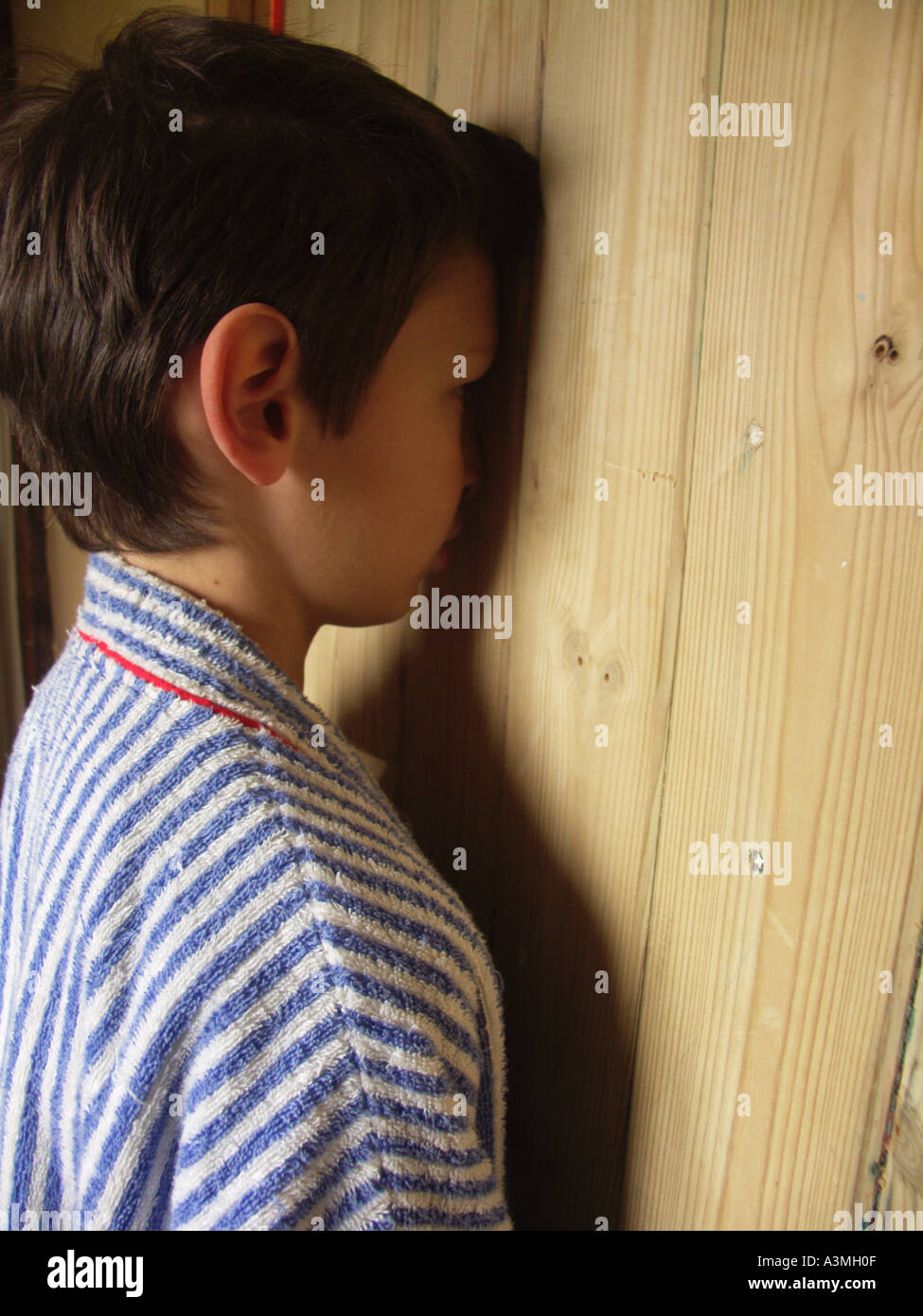 Boy facing wooden door or wall with side of head to camera Stock Photo ...