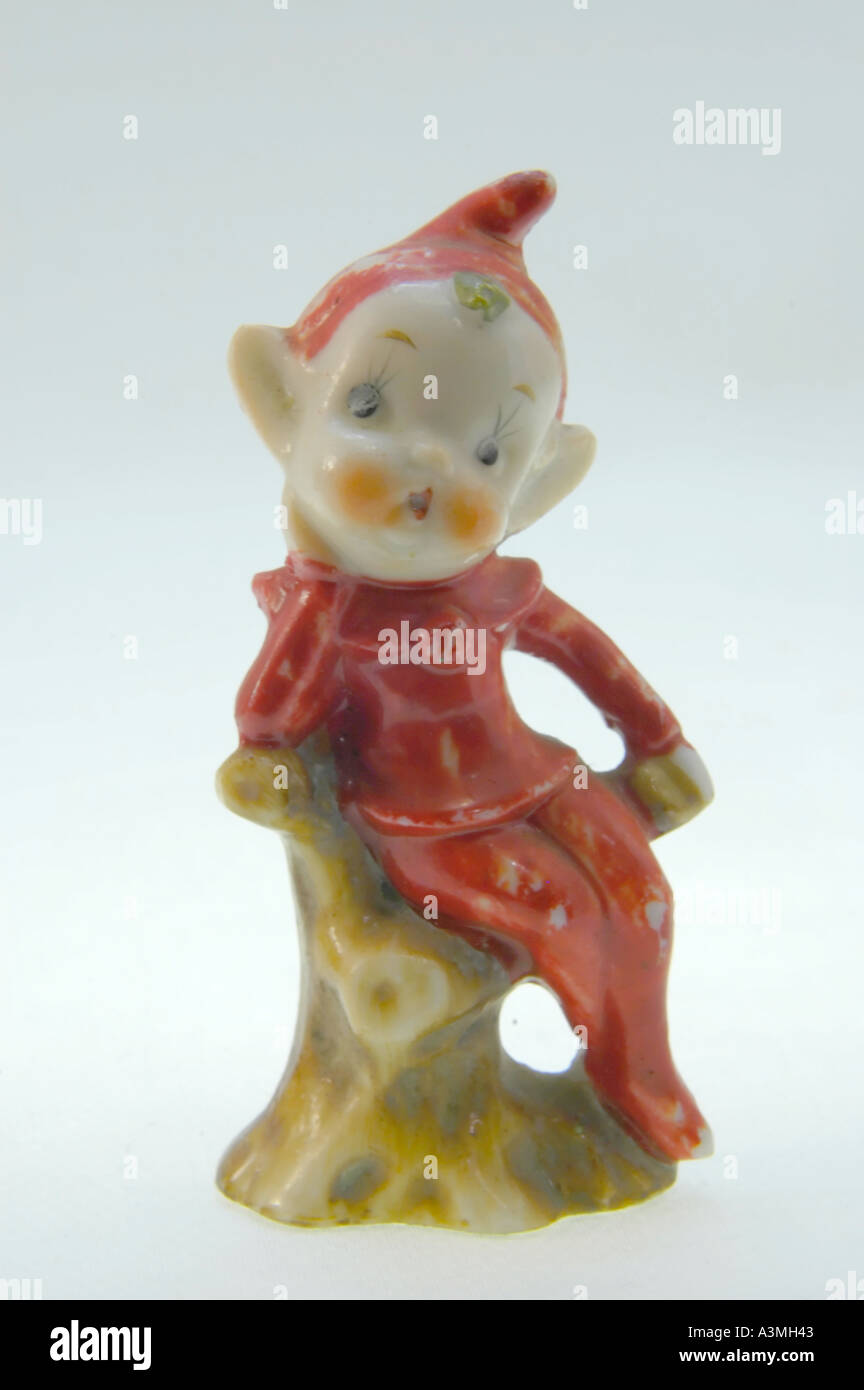 Antique ceramic pixie figurine in a red outfit sitting on a tree stump ...