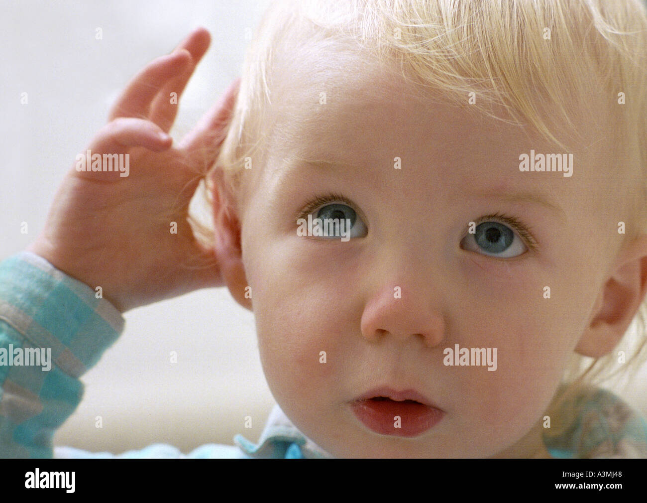 Blonde toddler boy touching his head Stock Photo - Alamy
