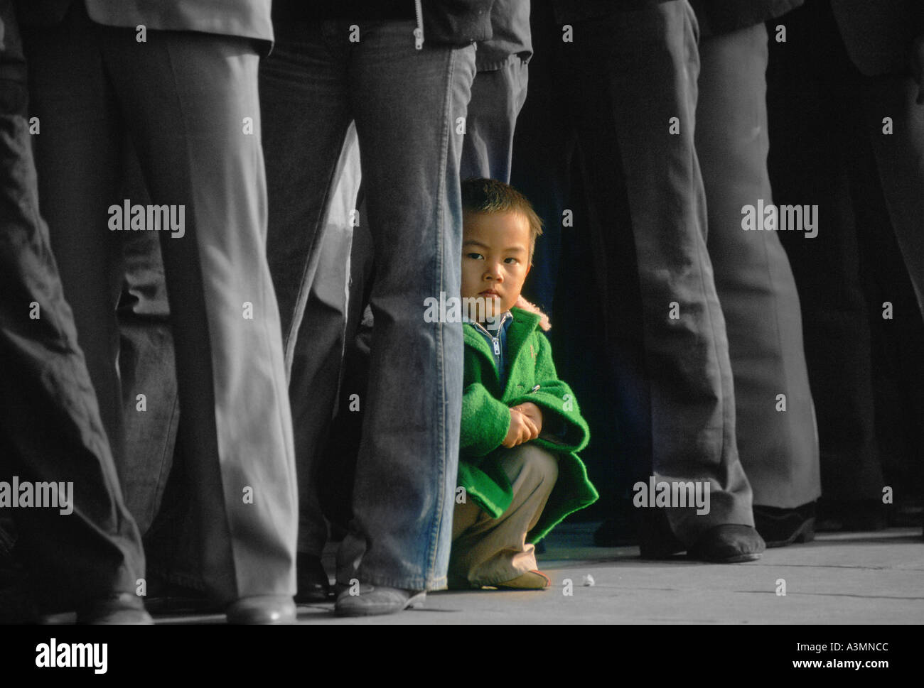 Young boy crouches down between adult legs in Beijing China Stock Photo ...