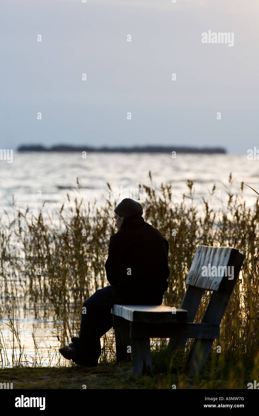 A man sitting alone on a bench at seaside at sunset , Finland Stock ...