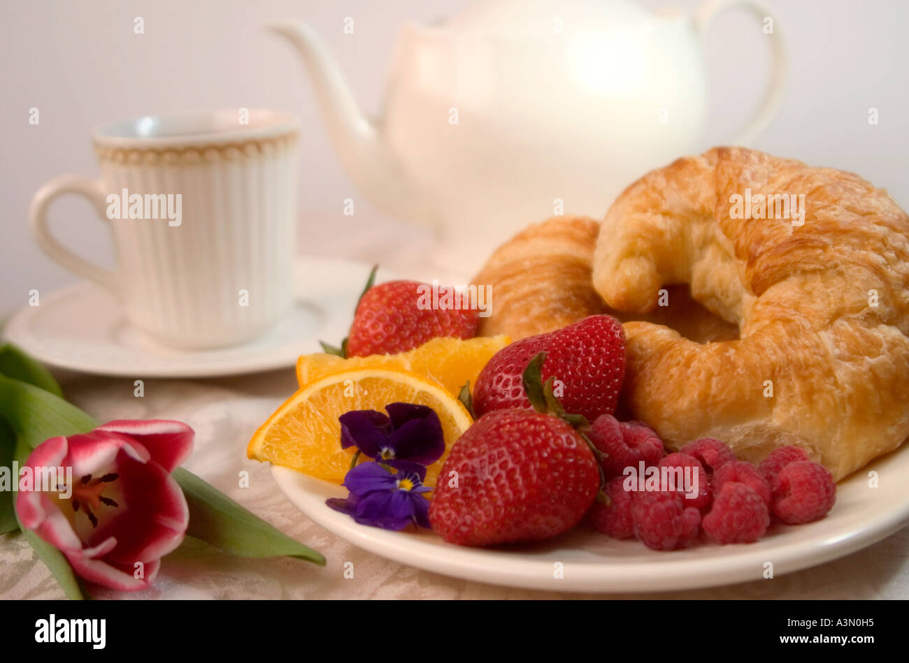 Mother's day brunch with croissants, fruit, tea, and spring flower ...