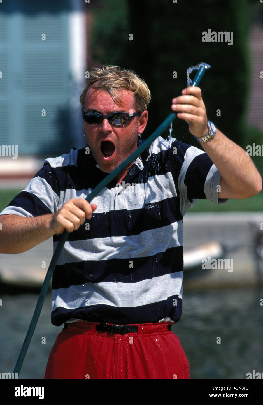 Fully clothed man soaked by hose pipe Stock Photo - Alamy
