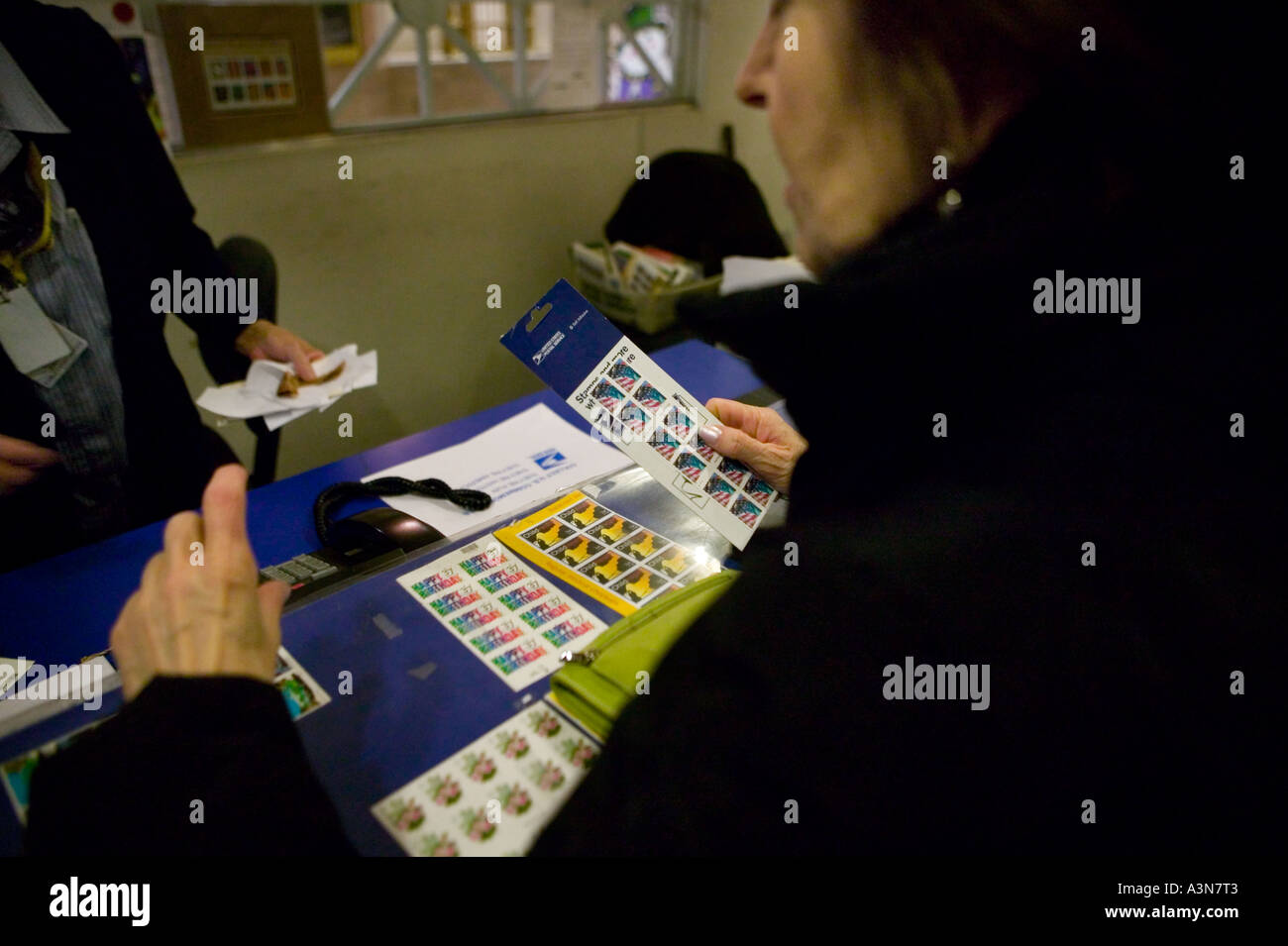 A woman buys stamps from a USPS employee at a counter at the James A ...