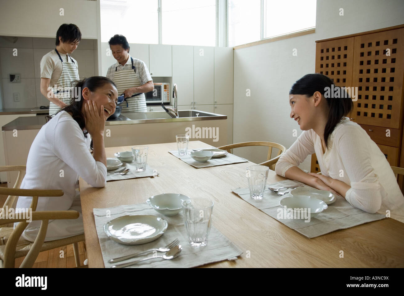 Mother and daughter cooking in kitchen while father and brother waiting ...