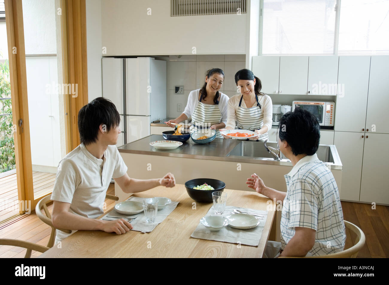 Mother and daughter cooking in kitchen while father and brother waiting ...