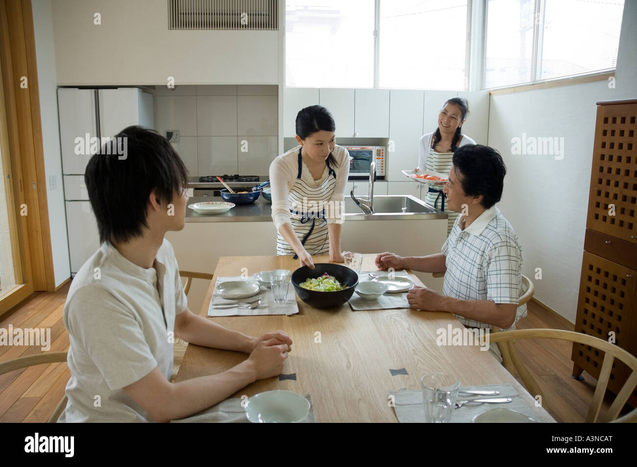Mother and daughter cooking in kitchen while father and brother waiting ...