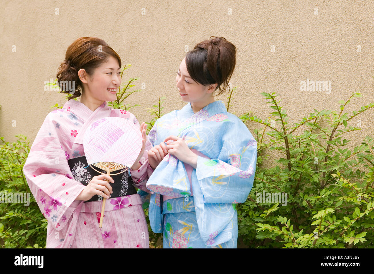 Two young women wearing yukata talking Stock Photo - Alamy