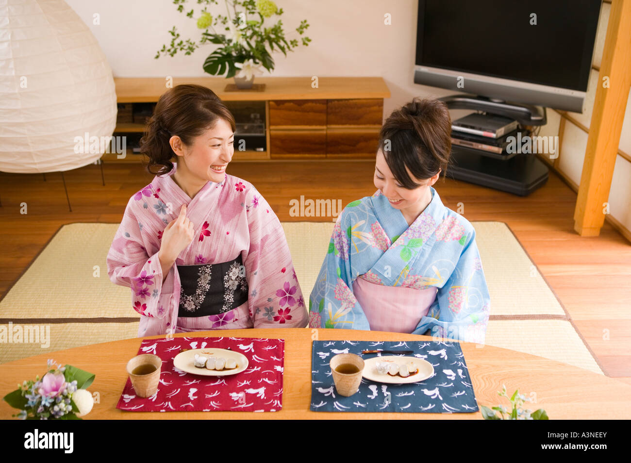Two young women wearing yukata sitting Stock Photo - Alamy