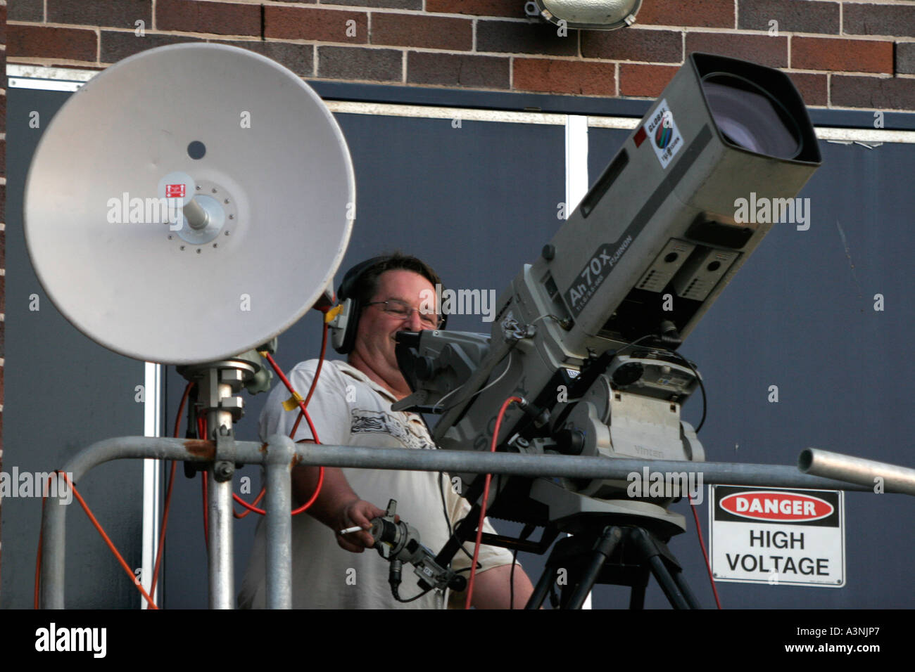 A Television Cameraman films with a satellite transmitter alongside him ...