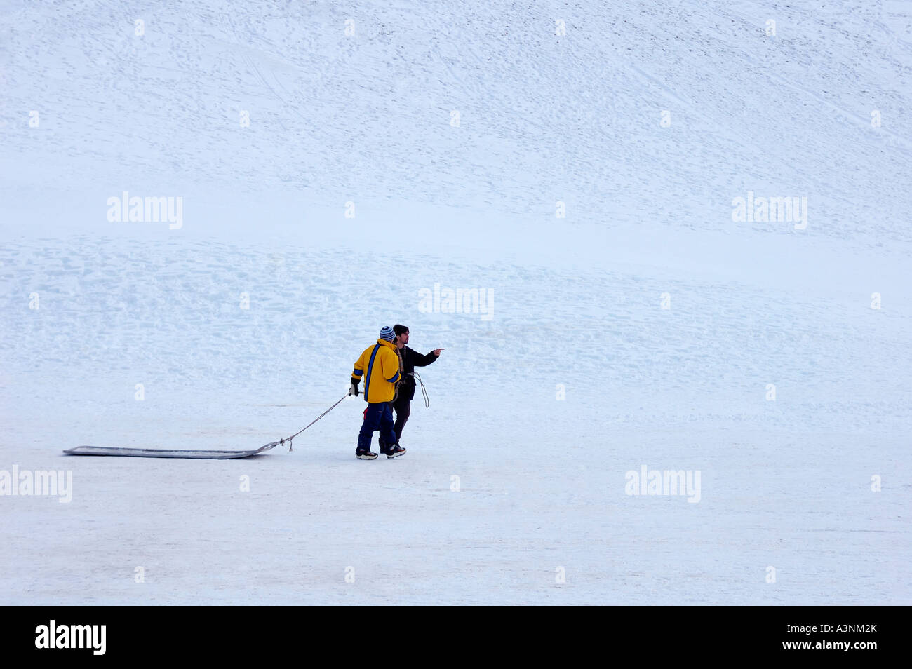 Two men pulling a sled in an icy wasteland Stock Photo - Alamy