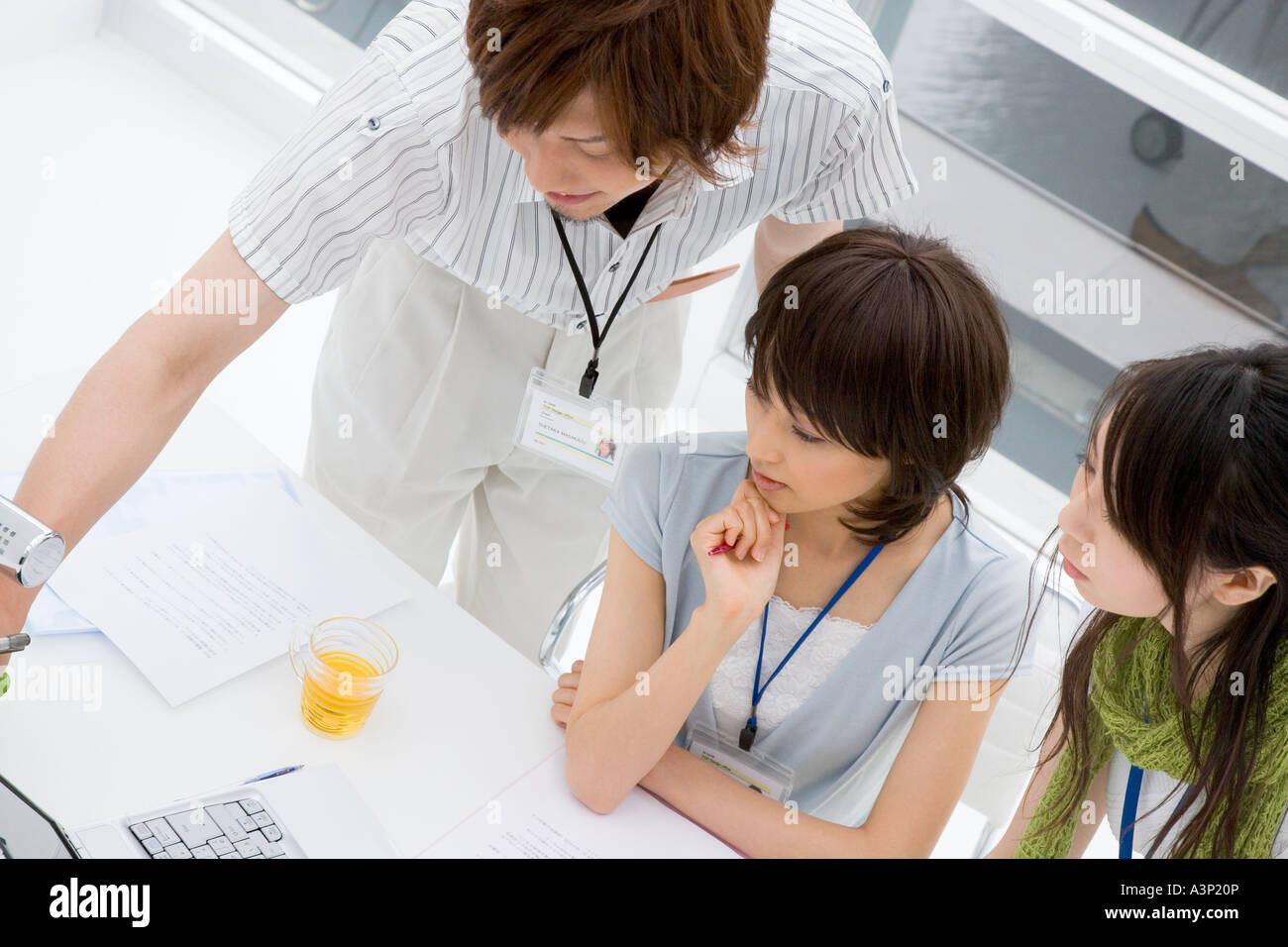 Three people looking at computer Stock Photo - Alamy