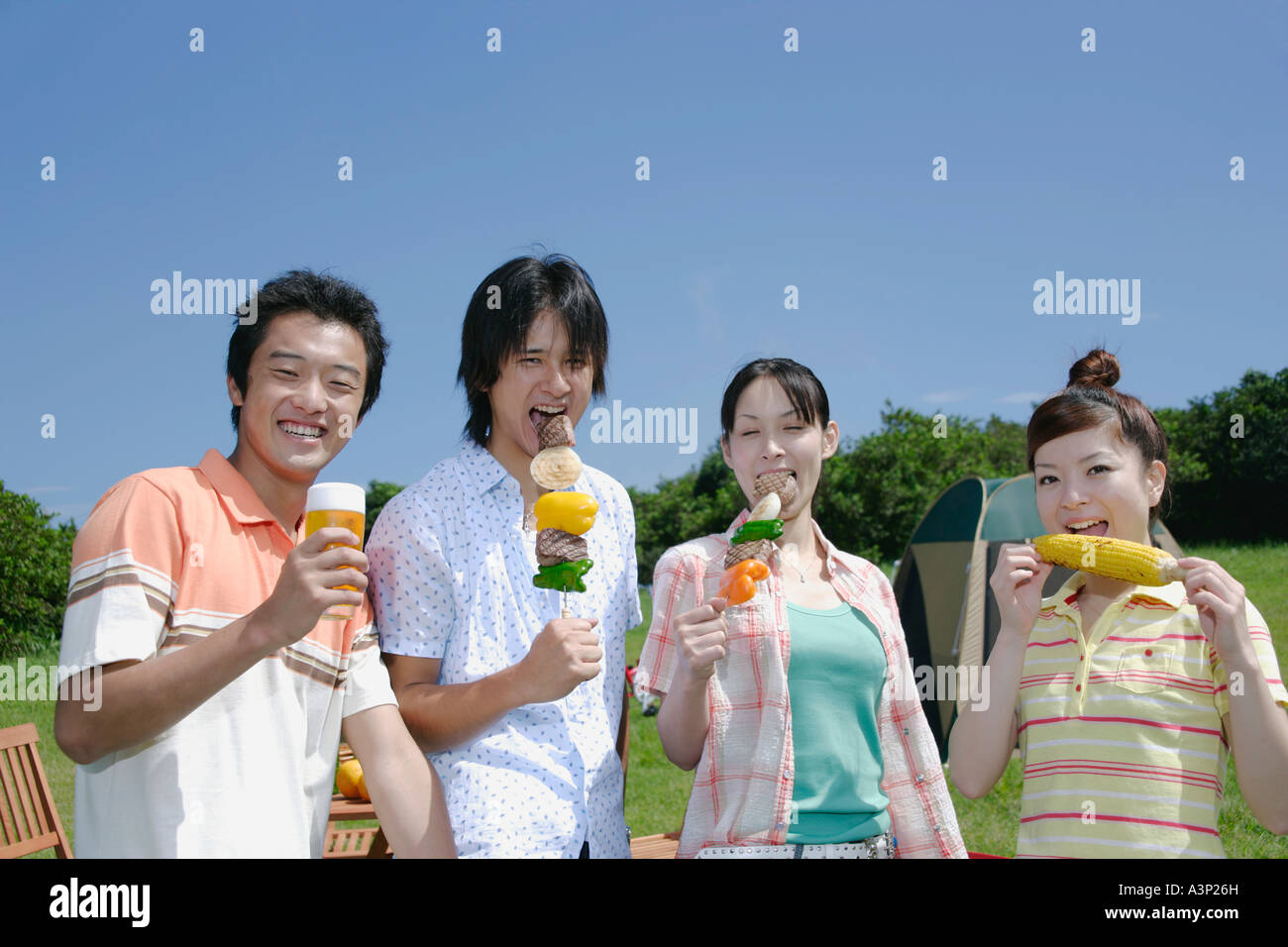 Four young people eating barbecue Stock Photo - Alamy