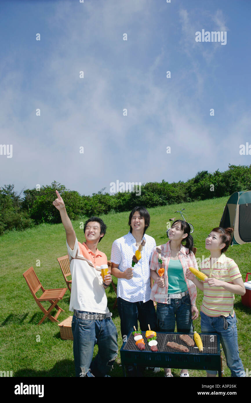 Four young people standing behind of barbecue grill Stock Photo - Alamy