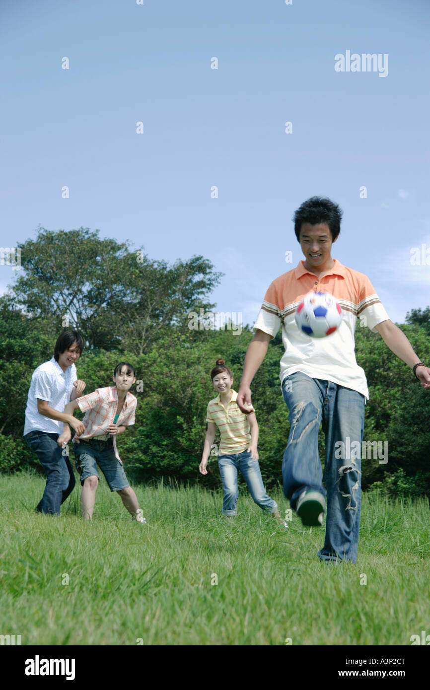 Four young people playing soccer Stock Photo - Alamy