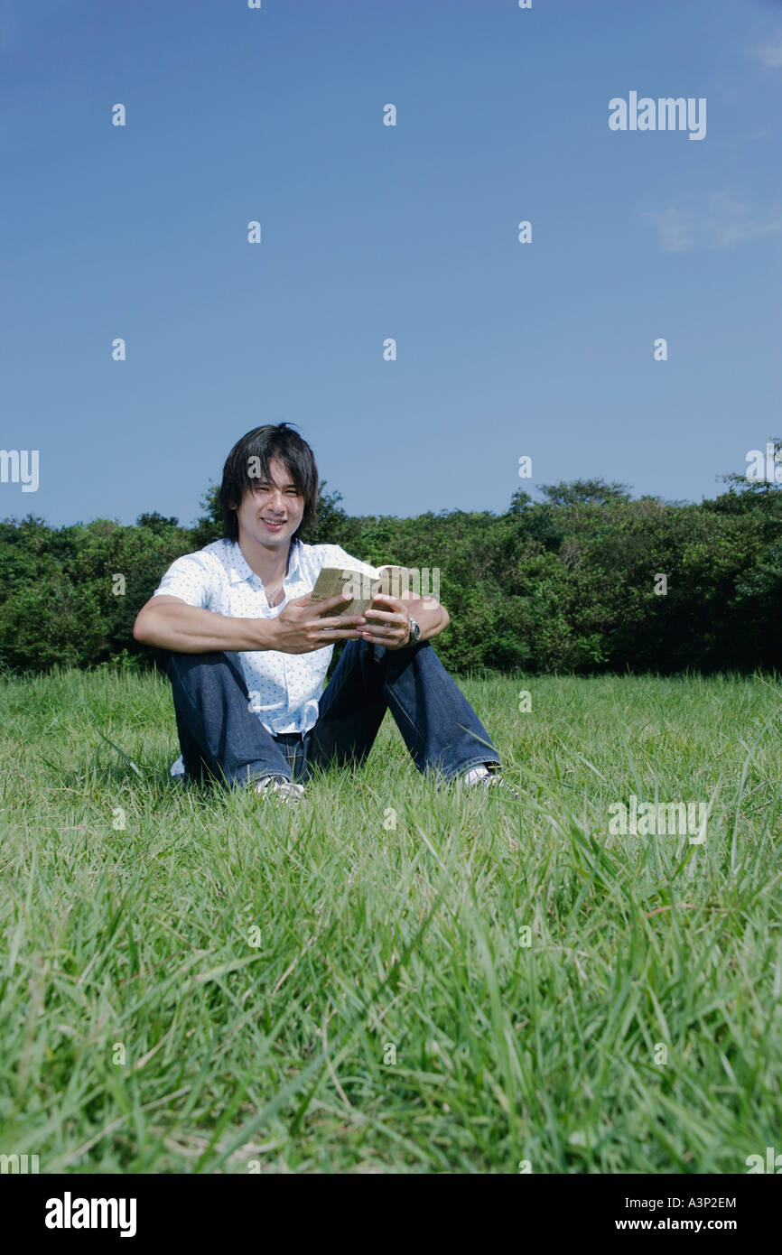 A young man reading a book on grass field Stock Photo - Alamy