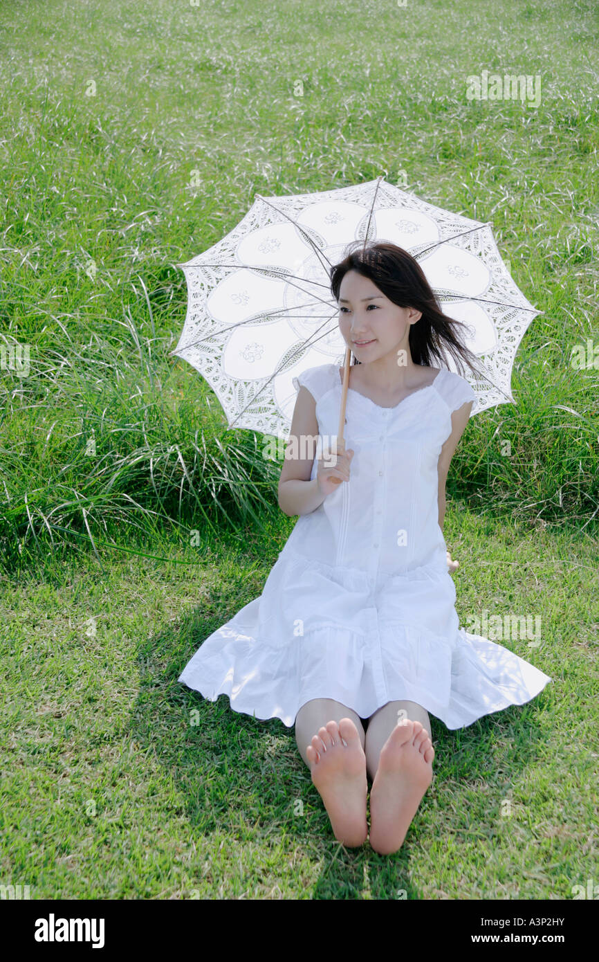 A young woman sitting on grass field Stock Photo - Alamy