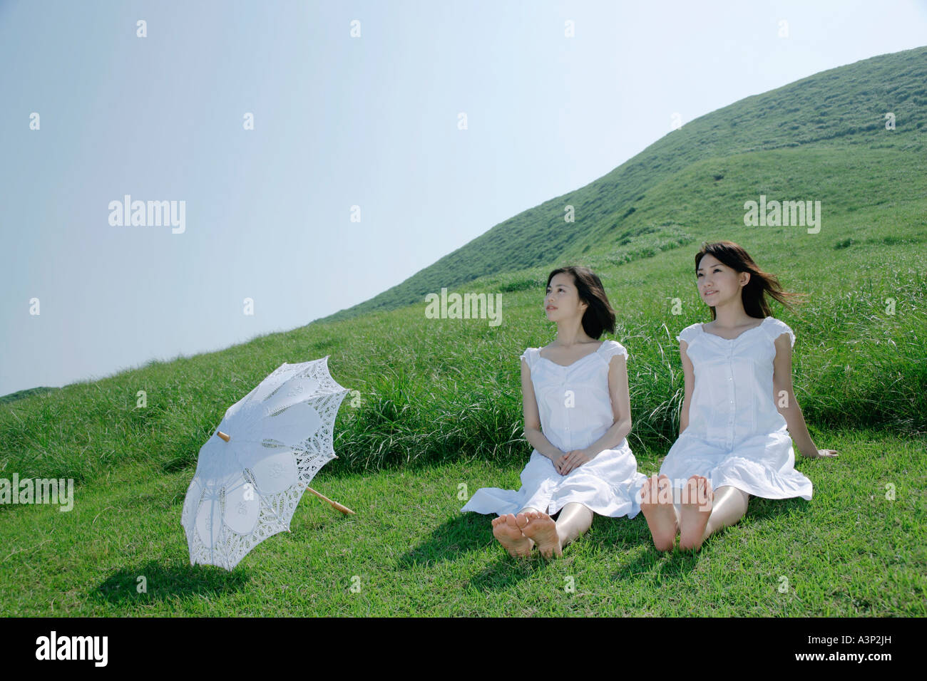 Two young women sitting on grass field Stock Photo - Alamy