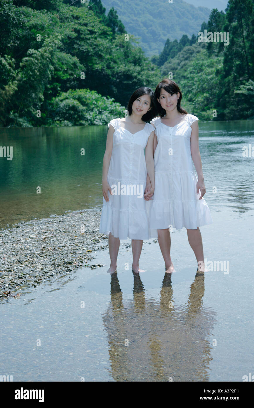 Two young women standing in river Stock Photo - Alamy