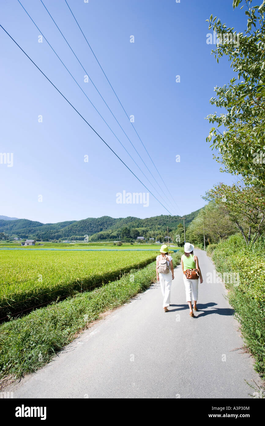 Two young women walking on rural road Stock Photo - Alamy