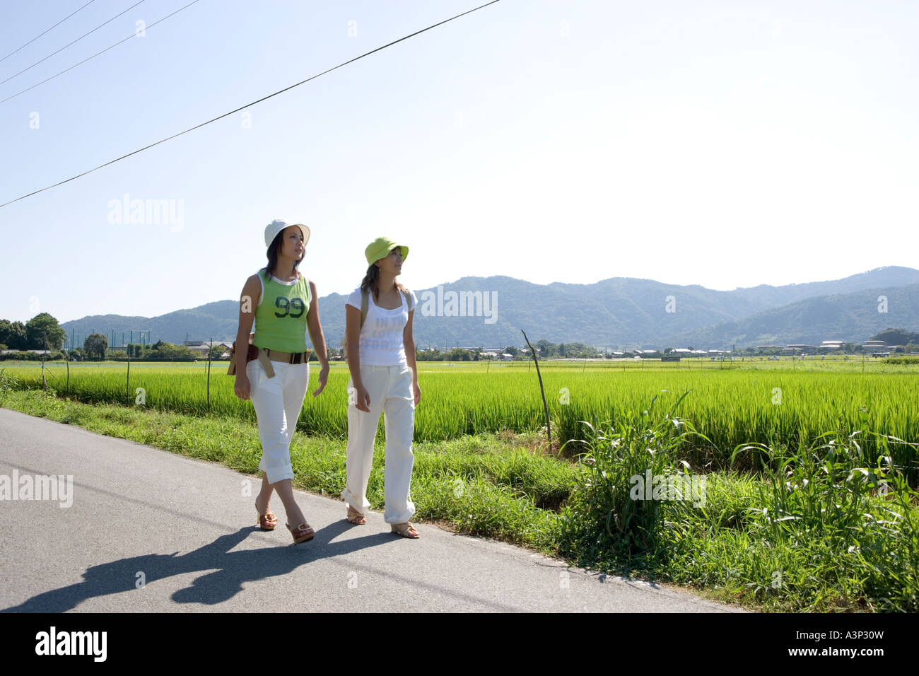 Two young women walking on rural road Stock Photo - Alamy