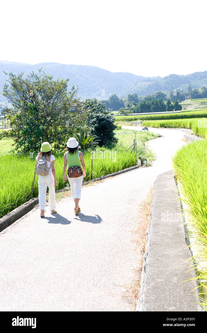 Two young women walking on rural road Stock Photo - Alamy