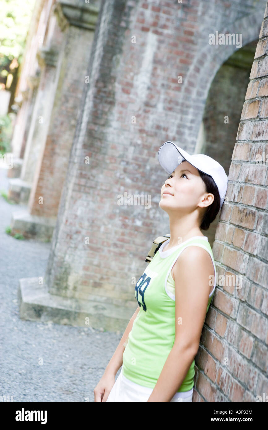 A young woman standing against brick wall Stock Photo - Alamy