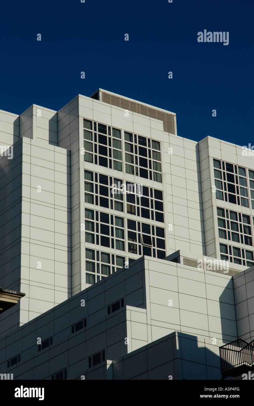 Irregularly shaped white modern office building against dark blue sky ...