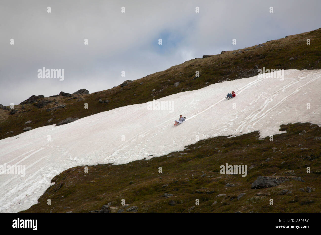 Two girls sliding down snow along Hatcher Pass Road , Alaska Stock ...