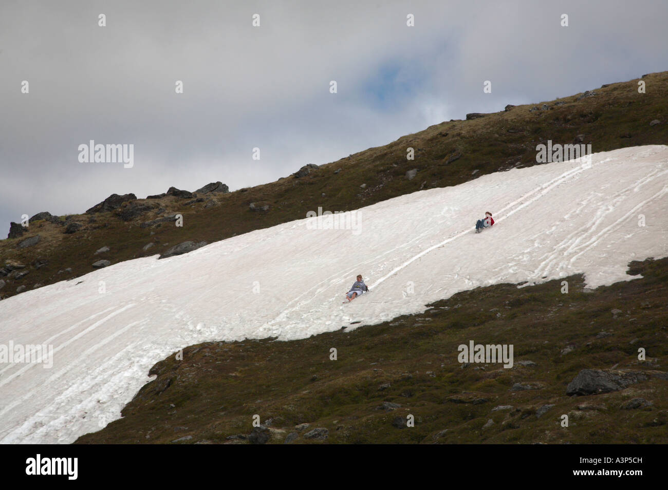 Two girls sliding down snow along Hatcher Pass Road , Alaska Stock ...